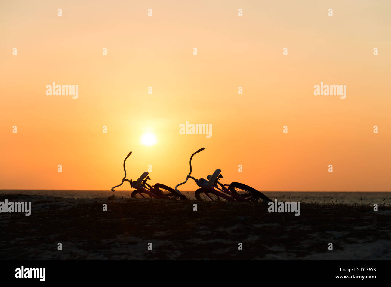 Two lying bikes silhouettes at the sunset on a beach Stock Photo - Alamy