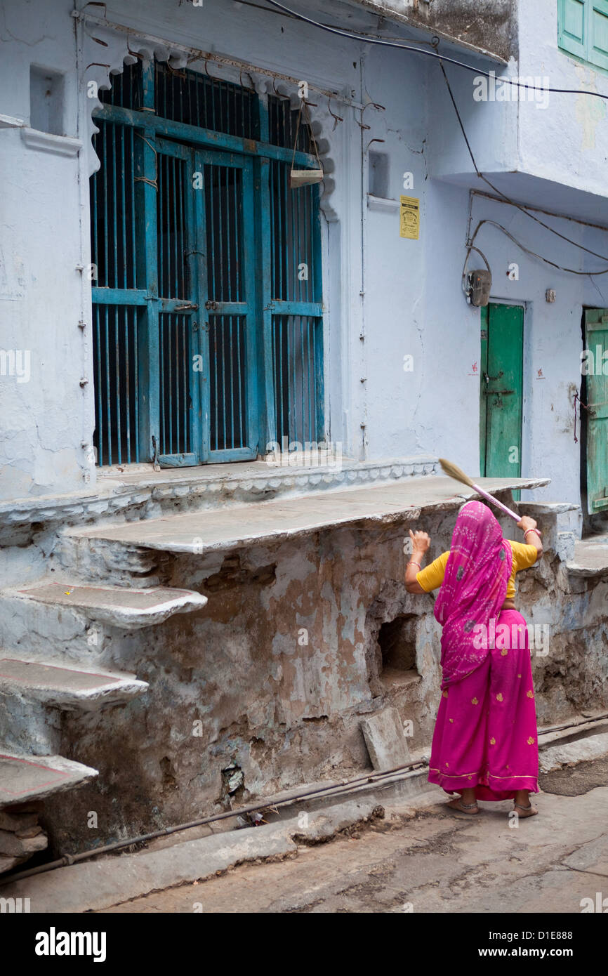 Indian woman in sari sweeping the steps outside her home in Udaipur ...