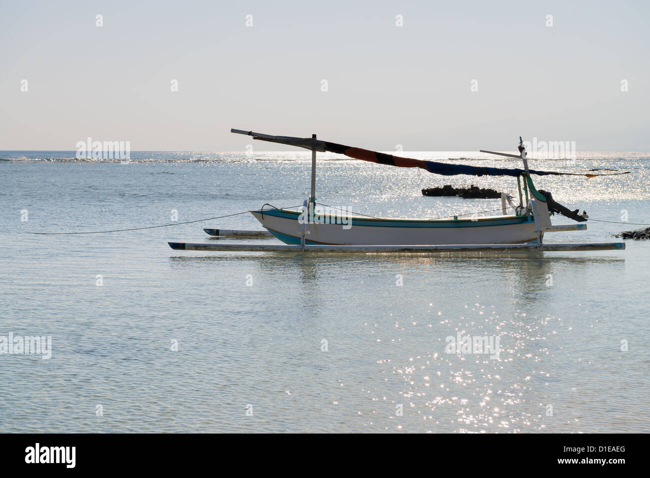Traditional indonesian boat on the surf of blue sea and back sun light ...