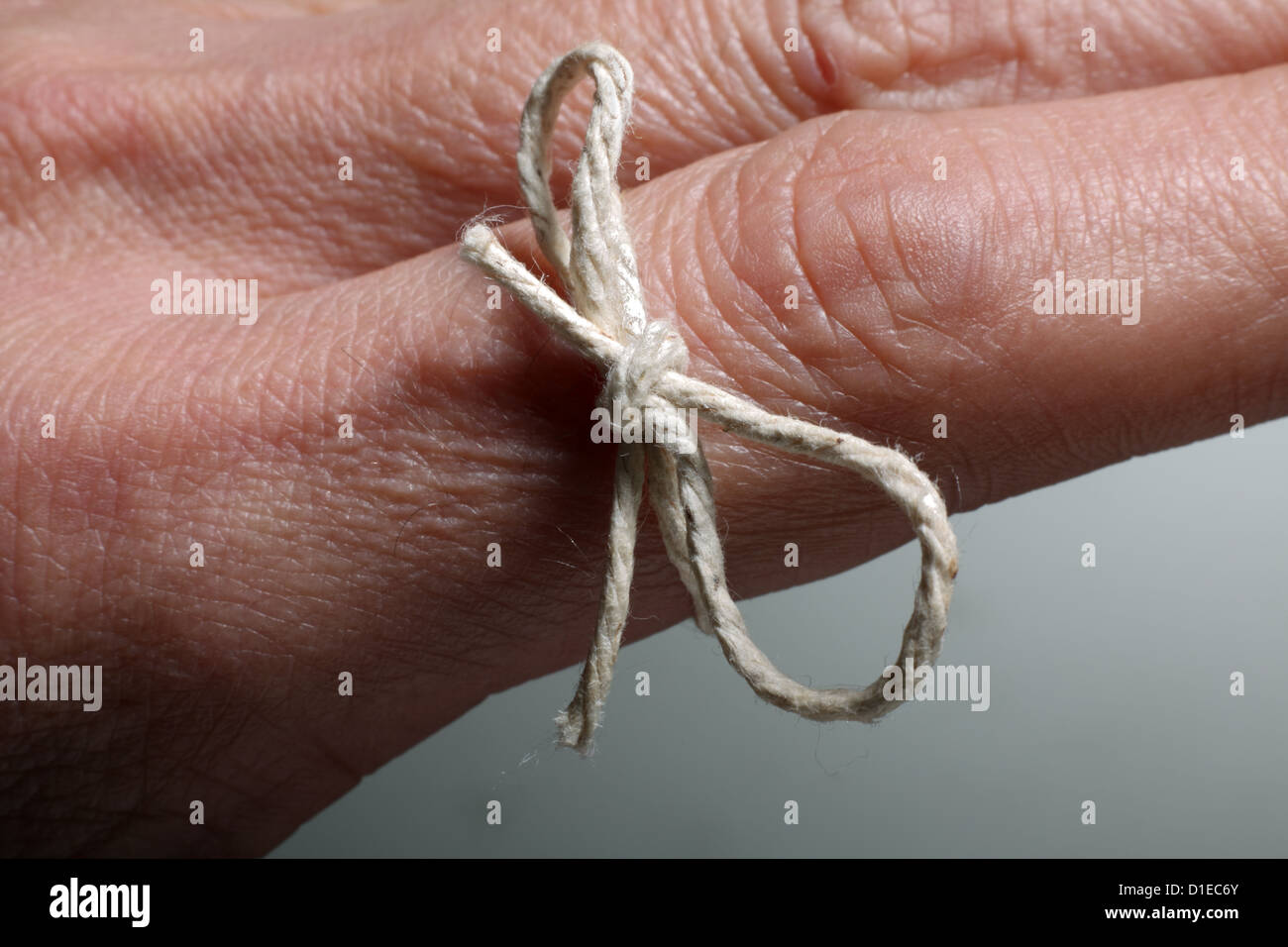 String tied around a mans finger as an aid to memory Stock Photo - Alamy