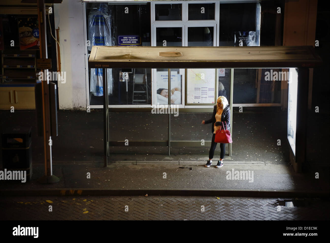 A young woman waiting alone at a bus stop at night in London UK Stock ...