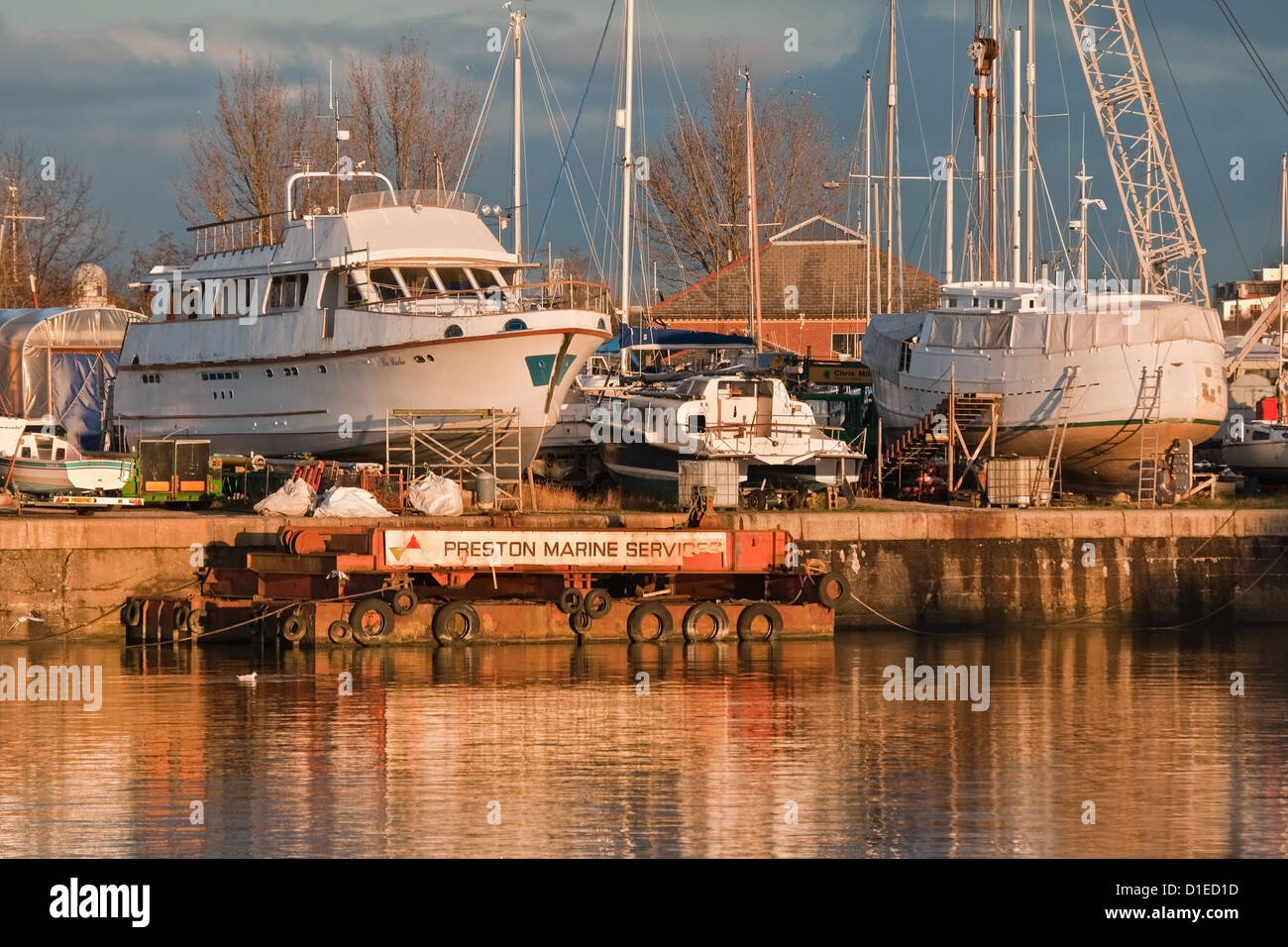 Warm late autumn sunshine bathes boats in the boatyard at Preston Docks ...
