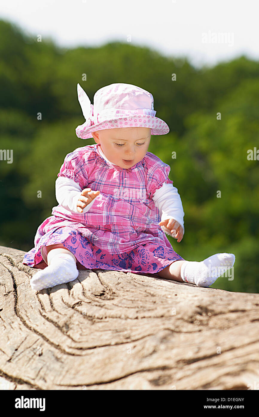 Female baby sitting on tree stump Stock Photo - Alamy