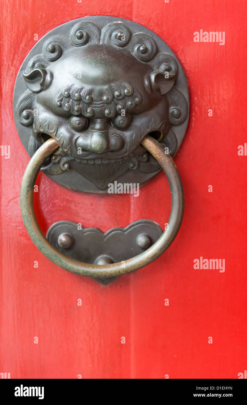 Old red Chinese door with decorative metal handle, selective focus on ...