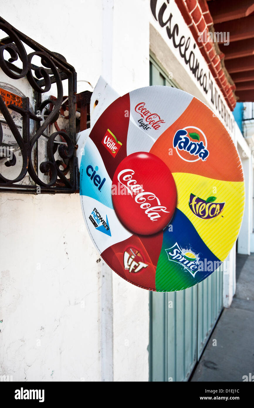 circular sign projecting from building with logos of Coca cola products ...