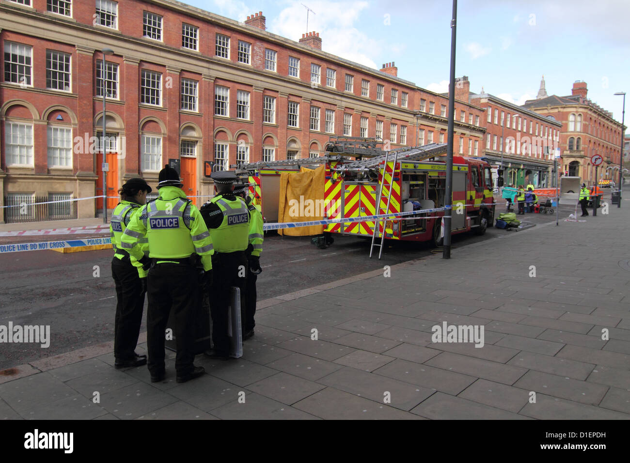 four UK police officers stood talking on roadside with fire engine in ...