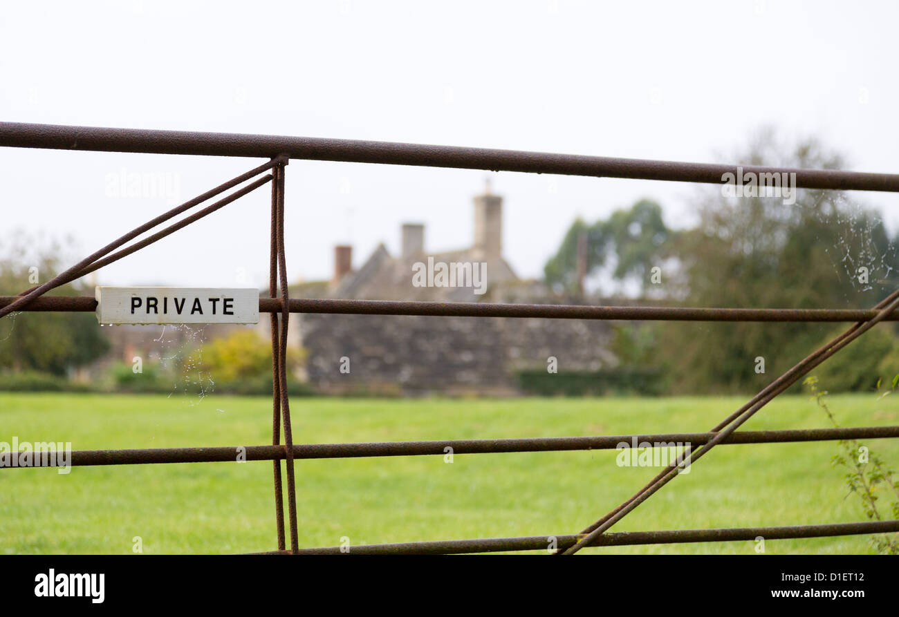 White painted private sign on iron metal farm gate in field with farm ...