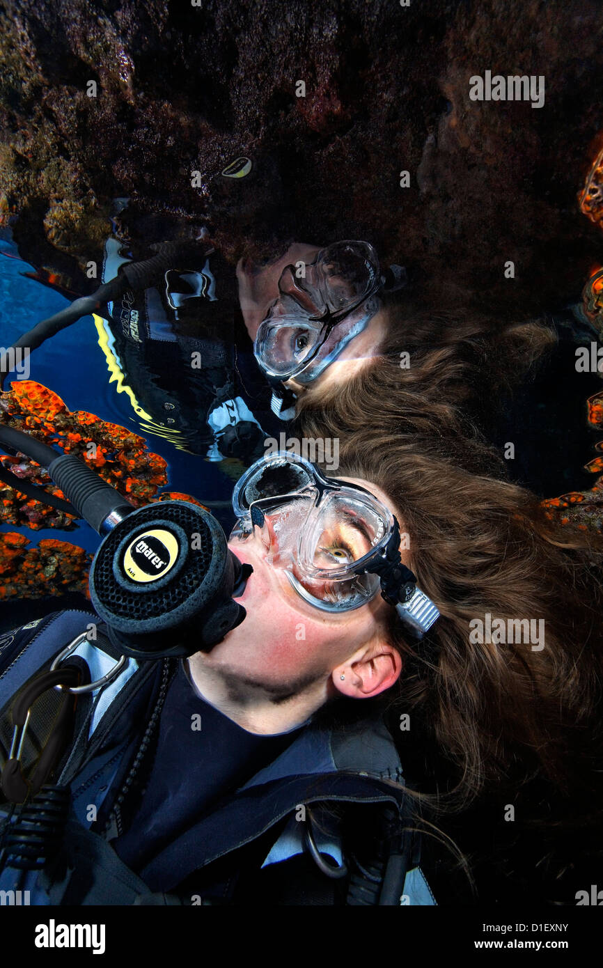 Female diver in a cave looking at her mirror image, Gozo, Mediterranean ...