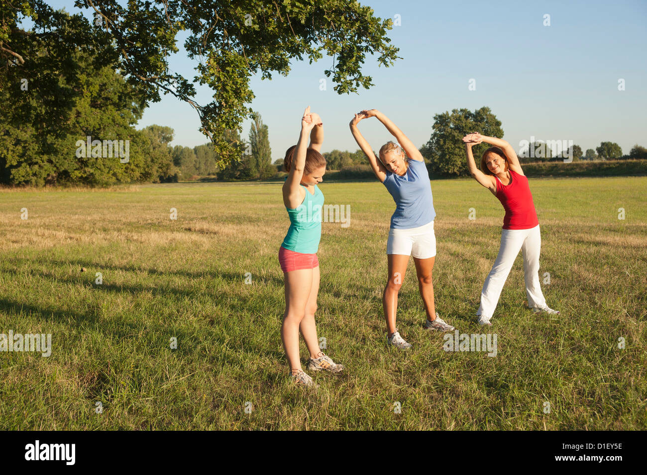Three women doing gymnastics on meadow Stock Photo - Alamy