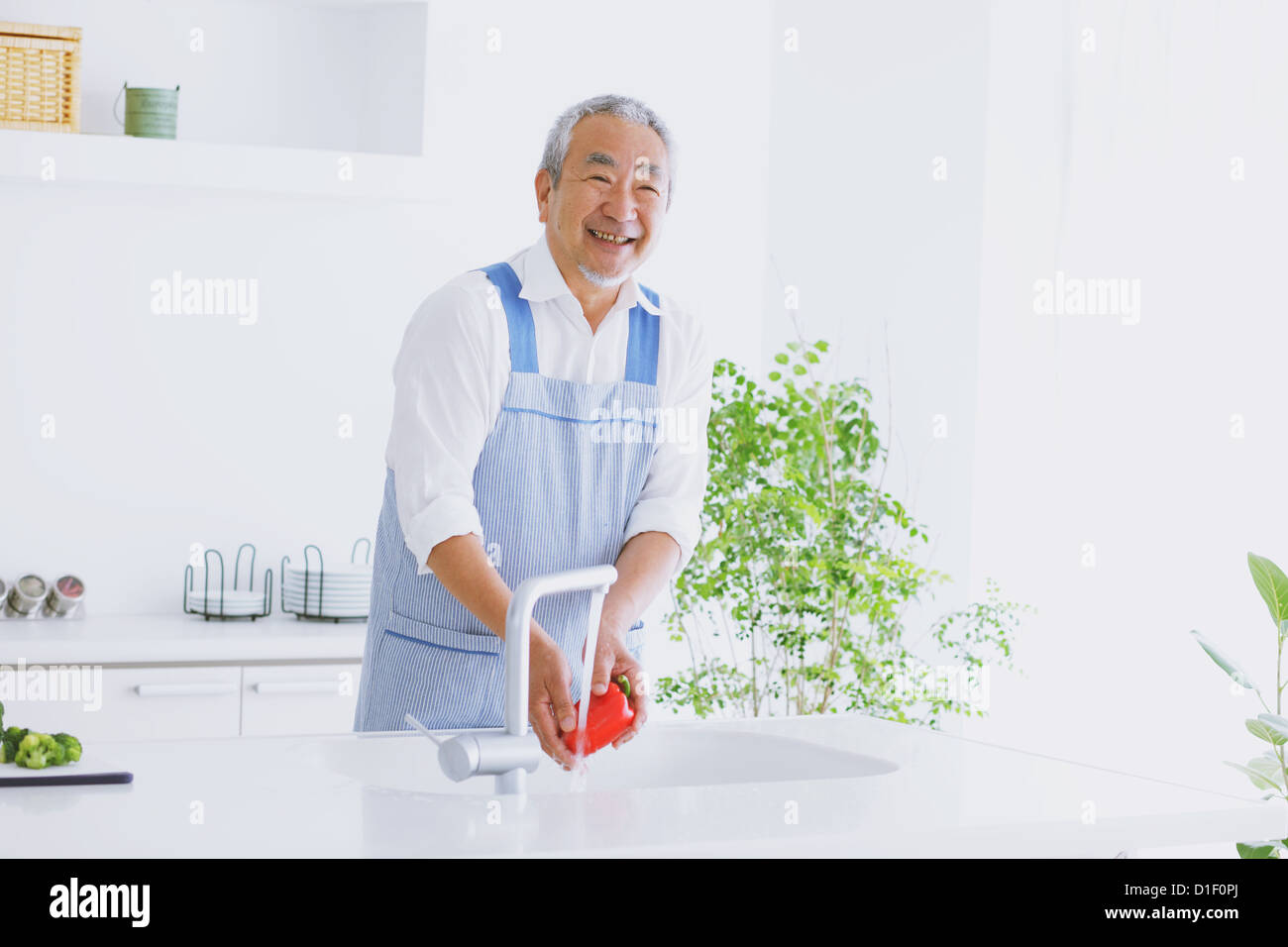 Senior adult man washing vegetables in an open kitchen Stock Photo - Alamy