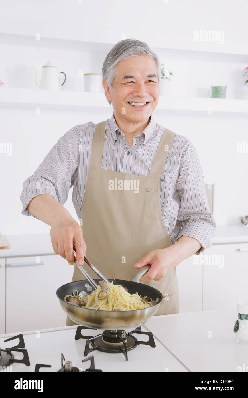 Senior adult man cooking pasta in an open kitchen Stock Photo - Alamy