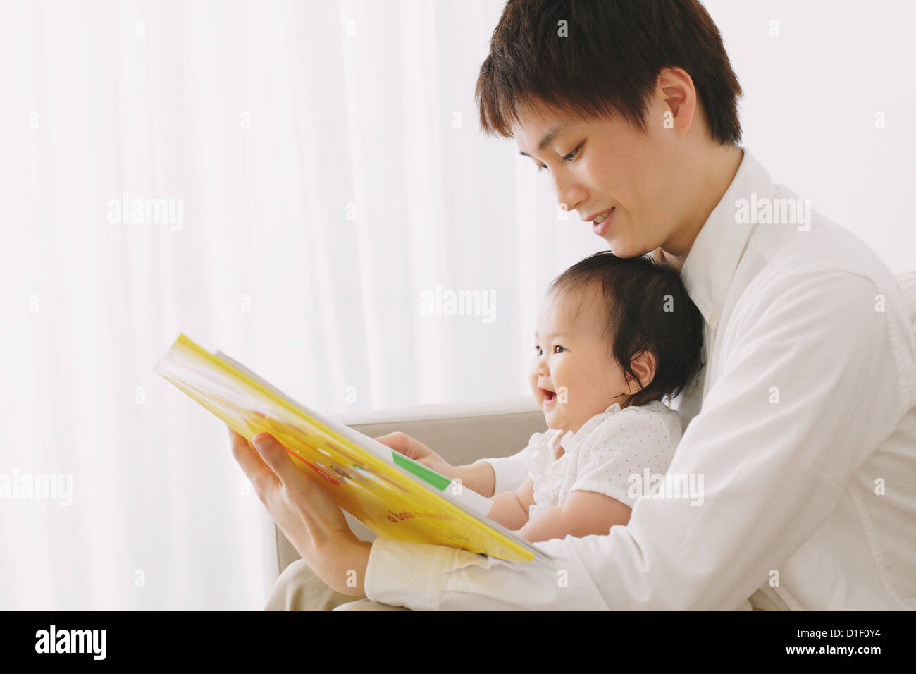 Father reading a baby book to his son on the sofa Stock Photo - Alamy