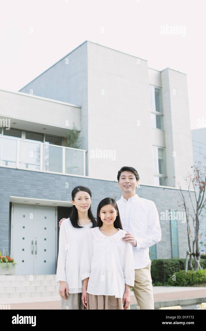Family of three people standing in front of their house smiling at ...