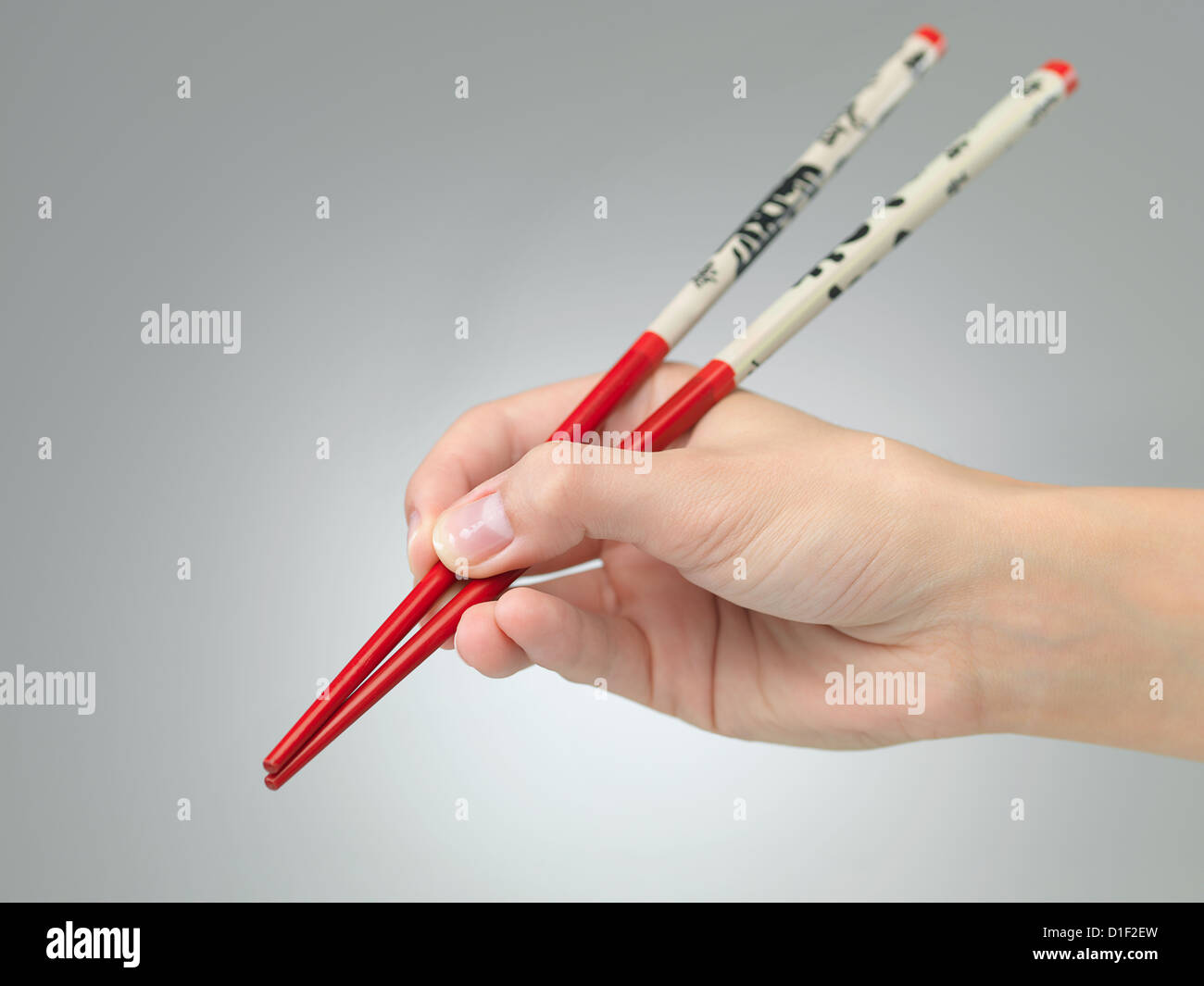 closeup of female hand holding chopsticks on grey gradient background ...