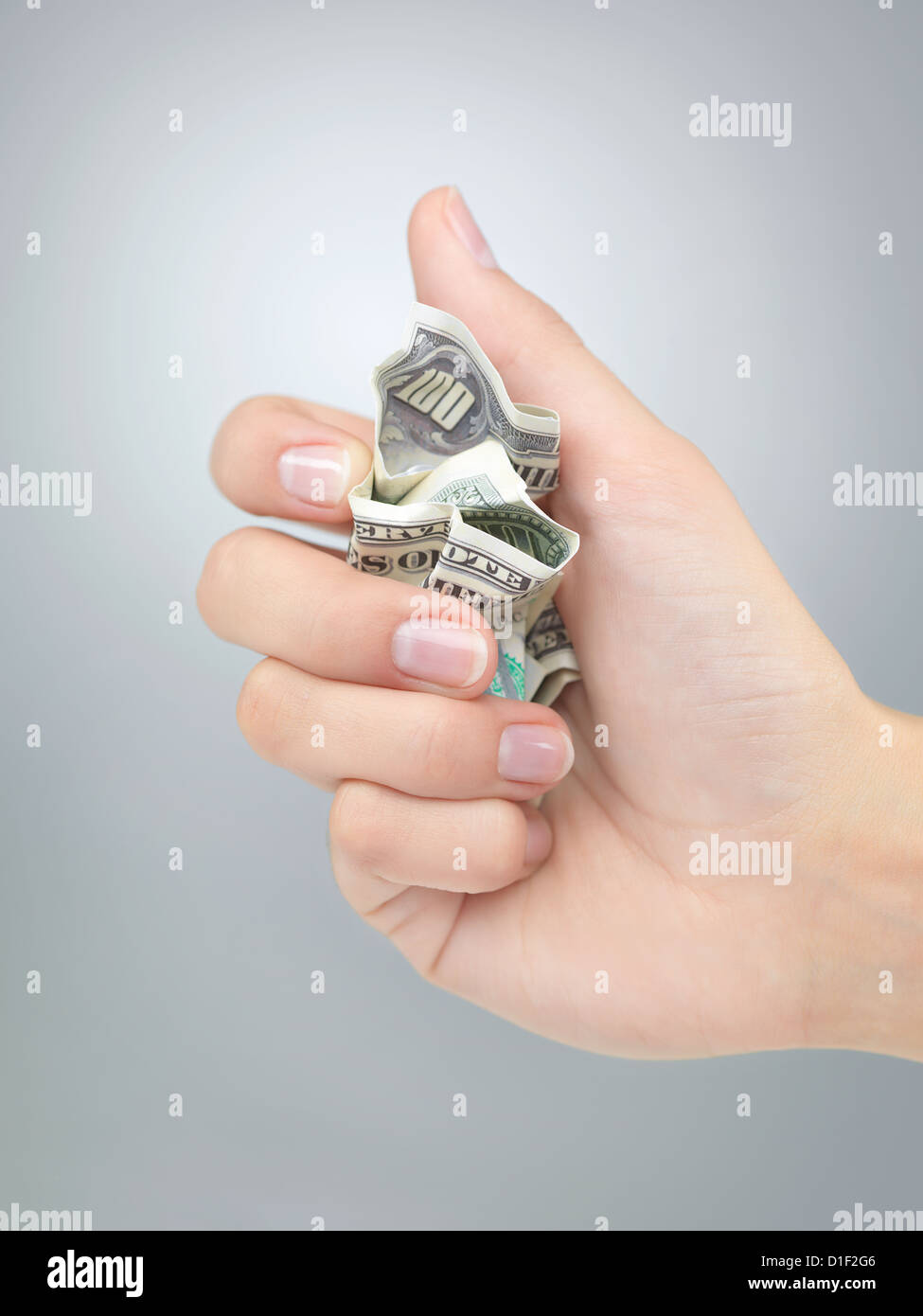 closeup of female hand holding a crumbled dollar bill on grey gradient ...