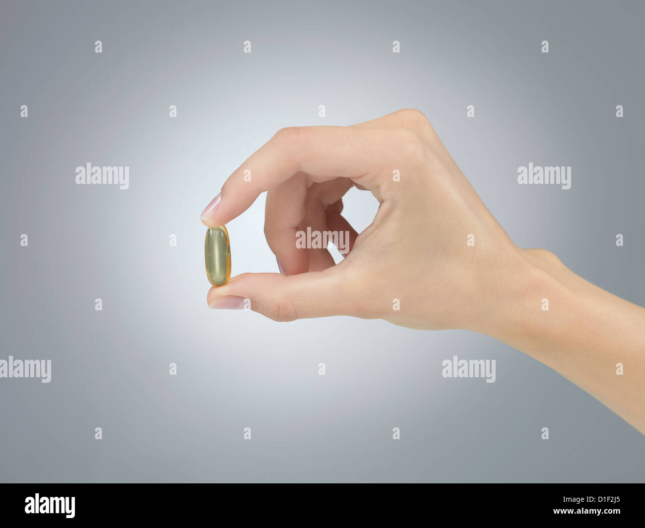 pill in fingers neutral gray gradient background Stock Photo - Alamy