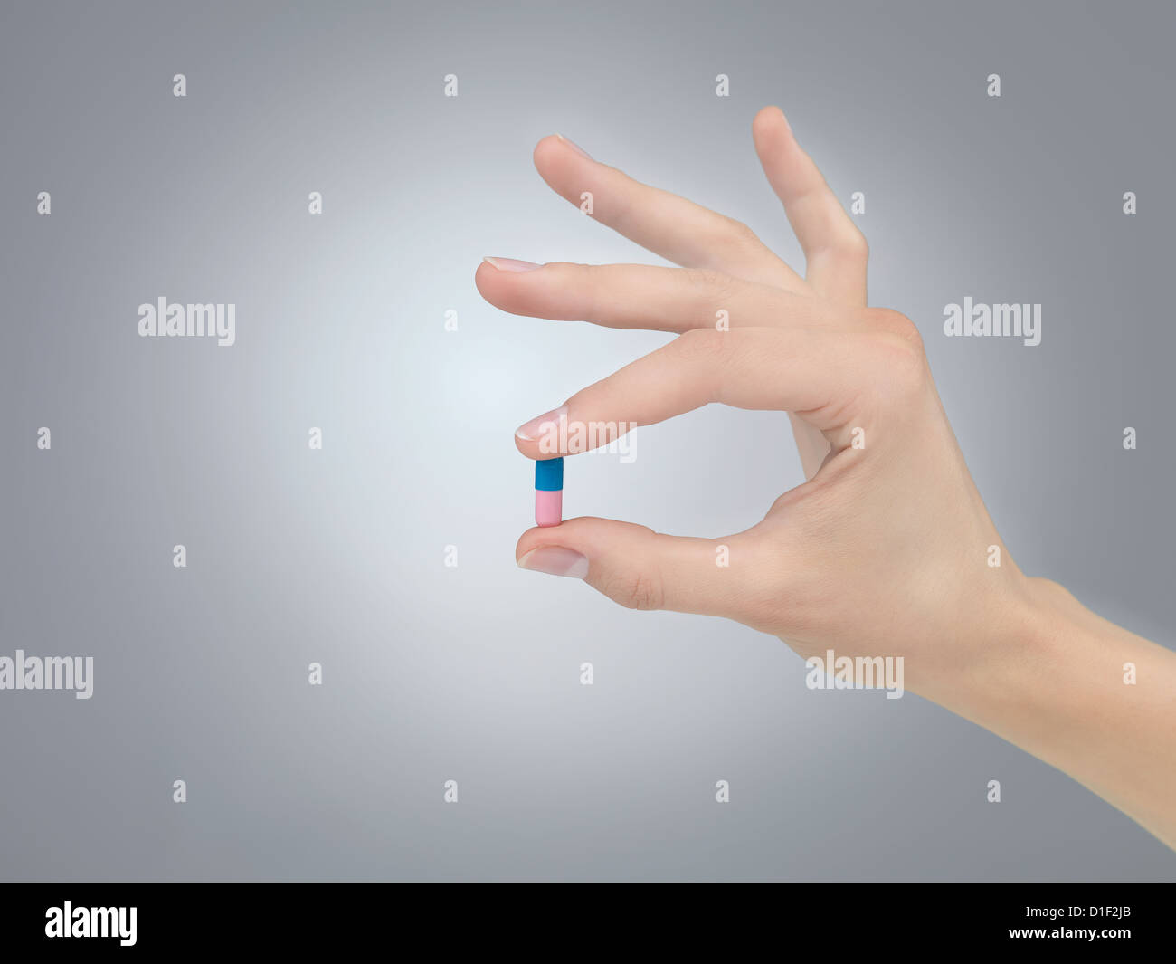pill in fingers neutral gray gradient background Stock Photo - Alamy