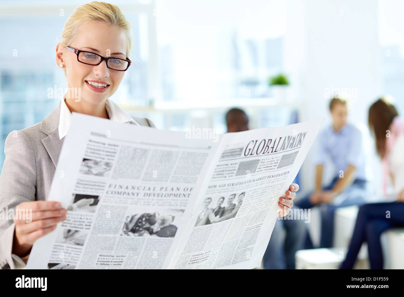 Portrait of happy female reading newspaper in working environment Stock ...