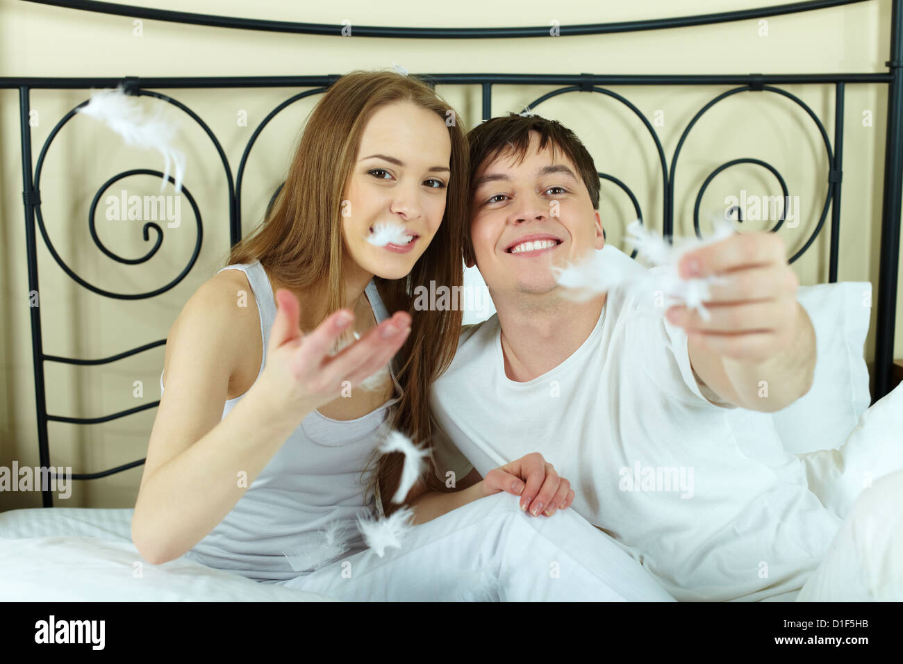 Happy couple playing with white feathers in bed Stock Photo - Alamy