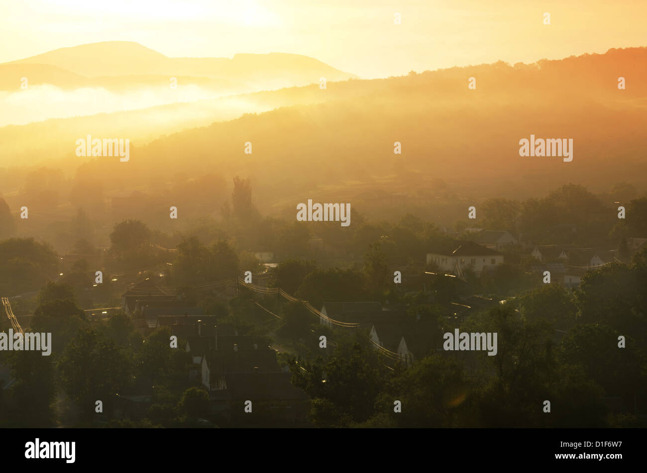 Mountain village landscape with sun and clouds Stock Photo - Alamy