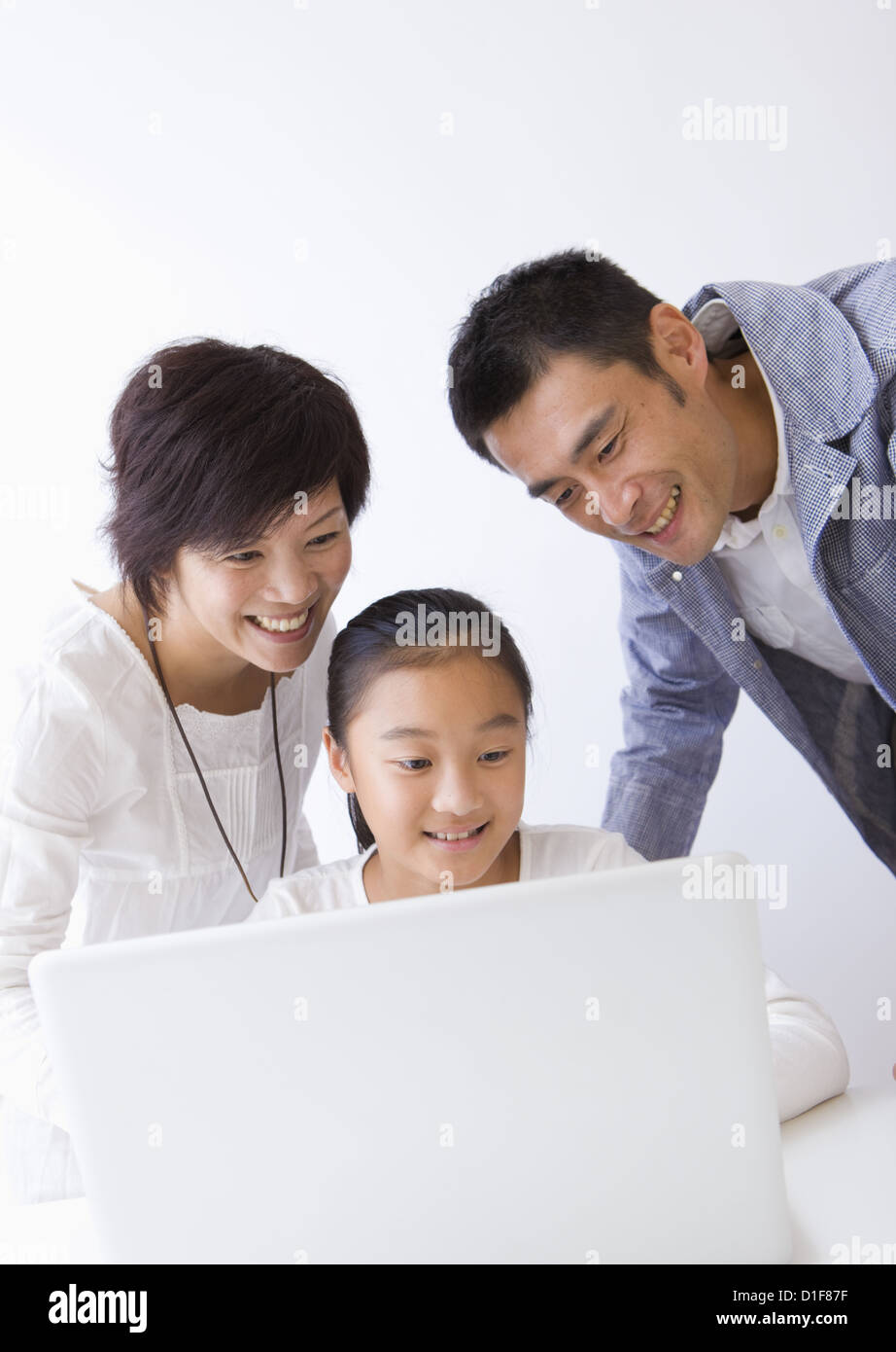 Girl and parents using a laptop Stock Photo - Alamy
