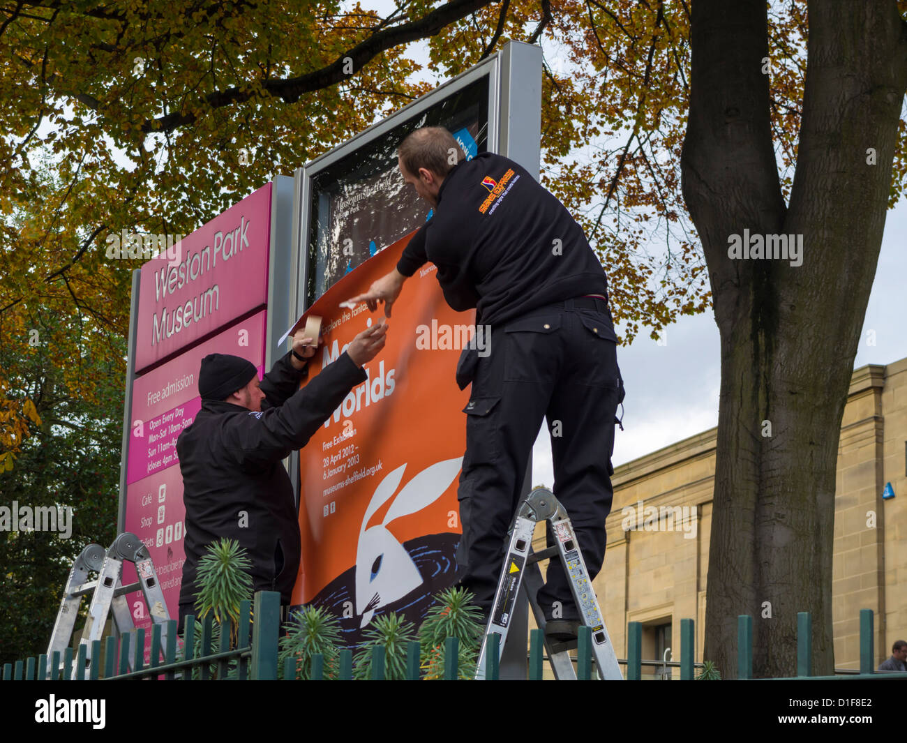 Two men putting up a new sign on a large billboard in Sheffield South ...