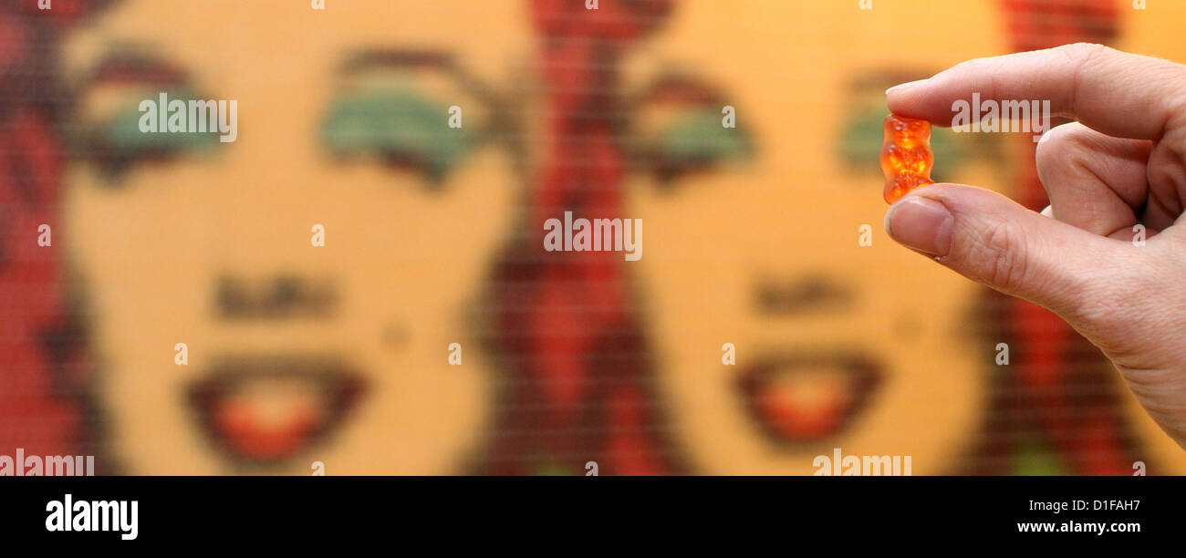 Artist Johannes Cordes holds a gummy bear in front of a pop art picture ...