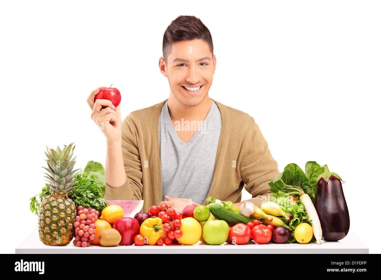Handsome smiling guy holding an apple and posing on a table full of ...