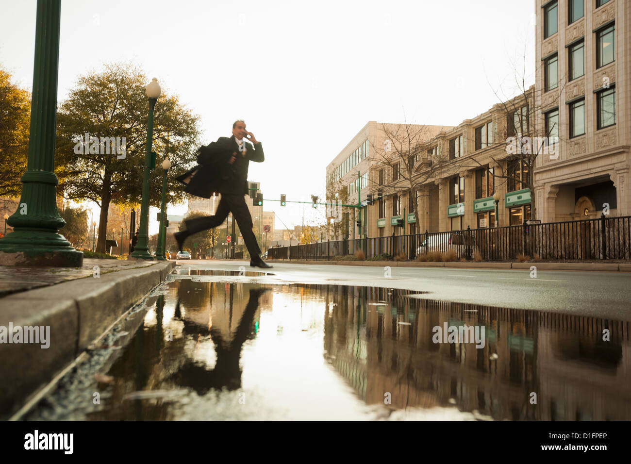 Caucasian businessman jumping over urban puddle Stock Photo - Alamy