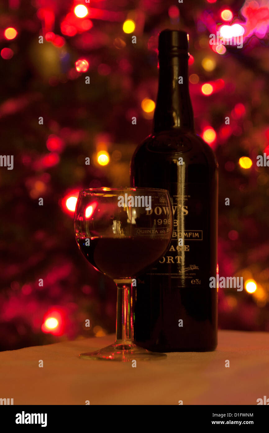 Bottle of port with glass on white table with Christmas tree with ...