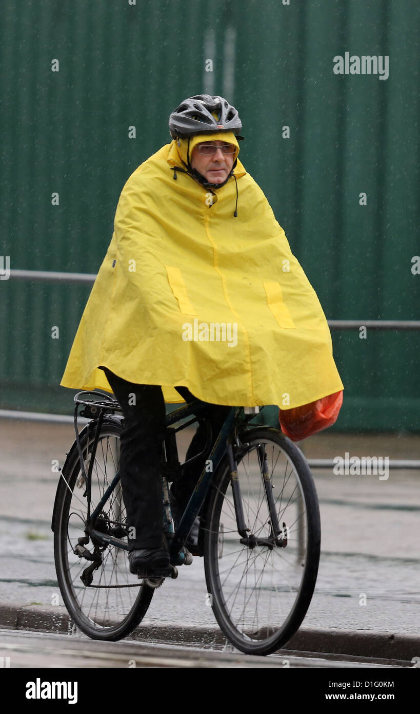 A cyclist in a bright yellow poncho cycles along Brighton seafront in ...