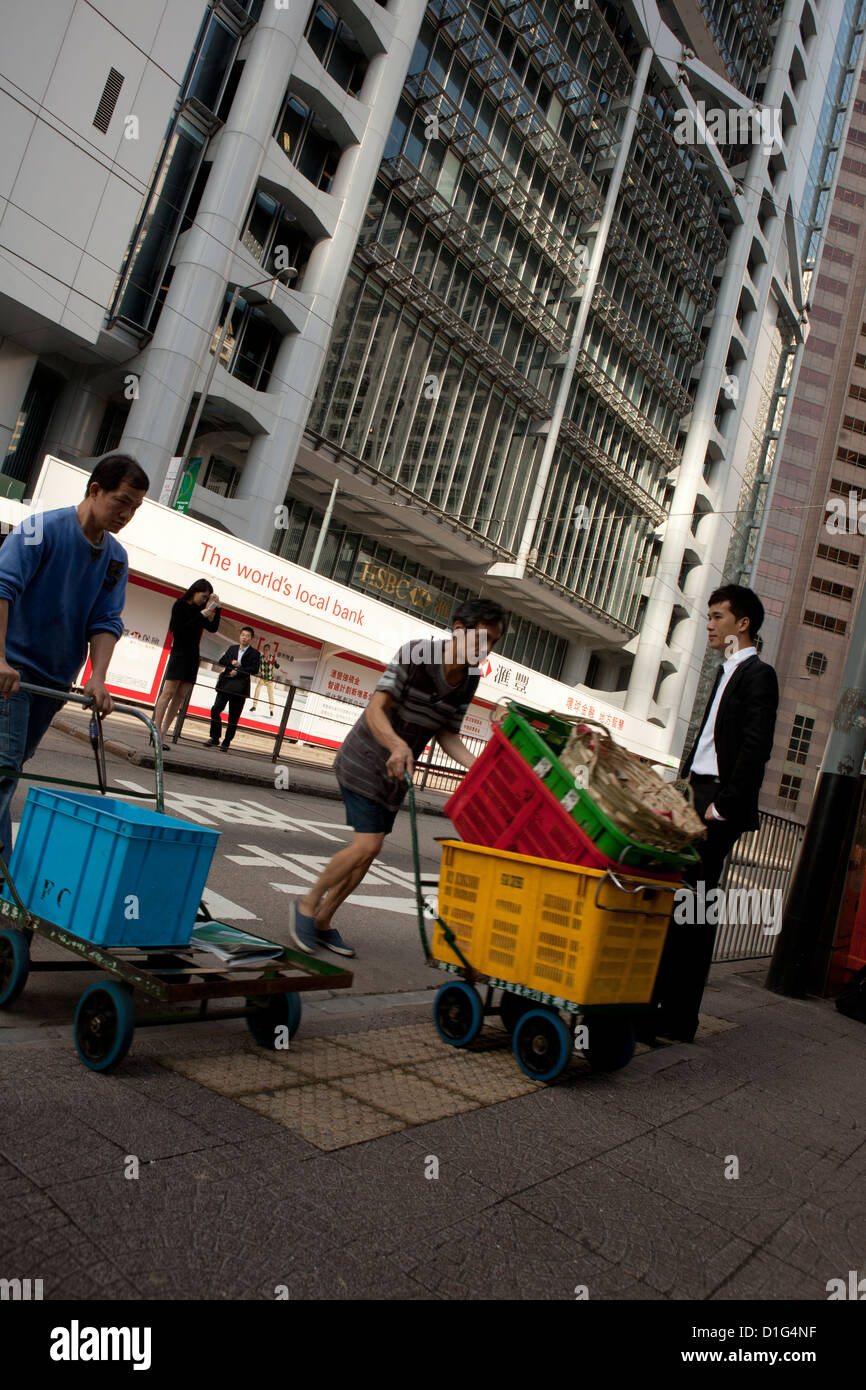 Workers push crates of goods in front of the HSBC headquarters building ...