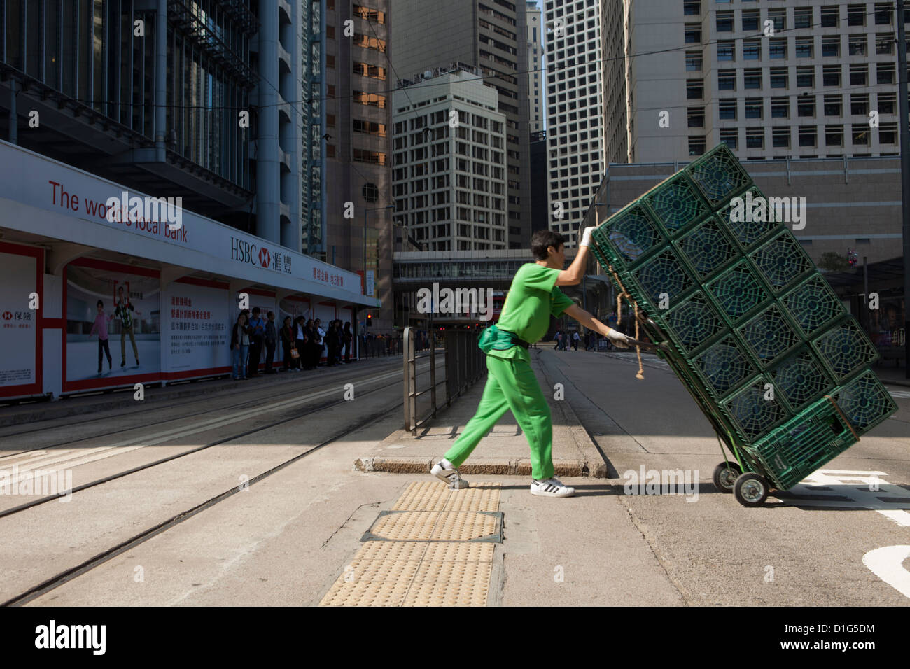 Worker pushes a trolley laden with bottled water in front of HSBC bank ...