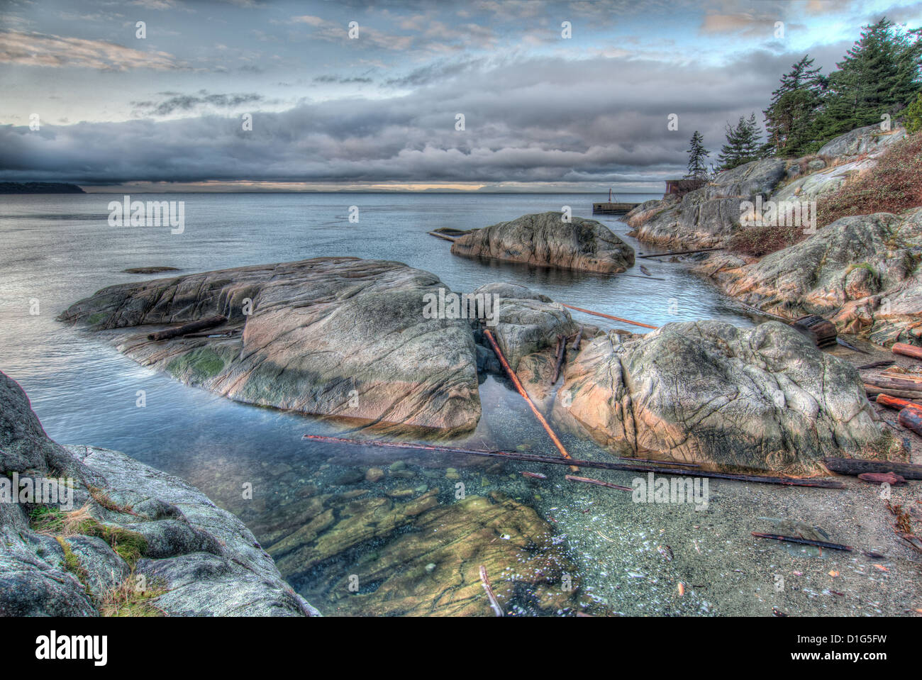 Rocky shoreline with clear water on grey morning Stock Photo - Alamy