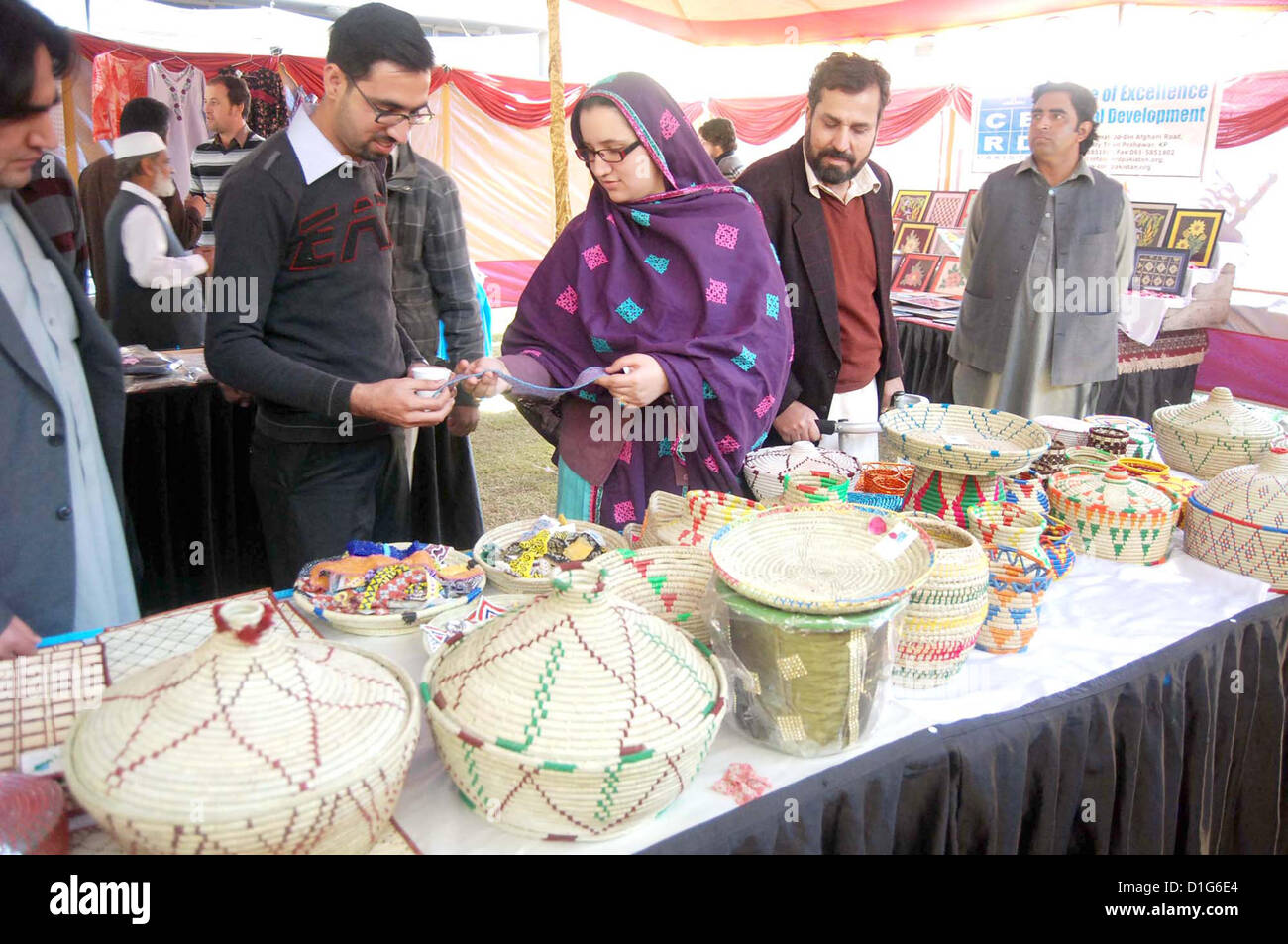 People take keen interest in hand-made goods at a stall during an ...