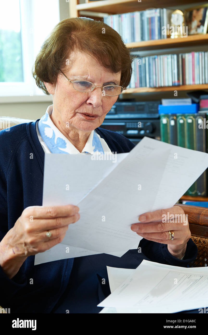 Senior woman at home reading utility bills looking worried and ...