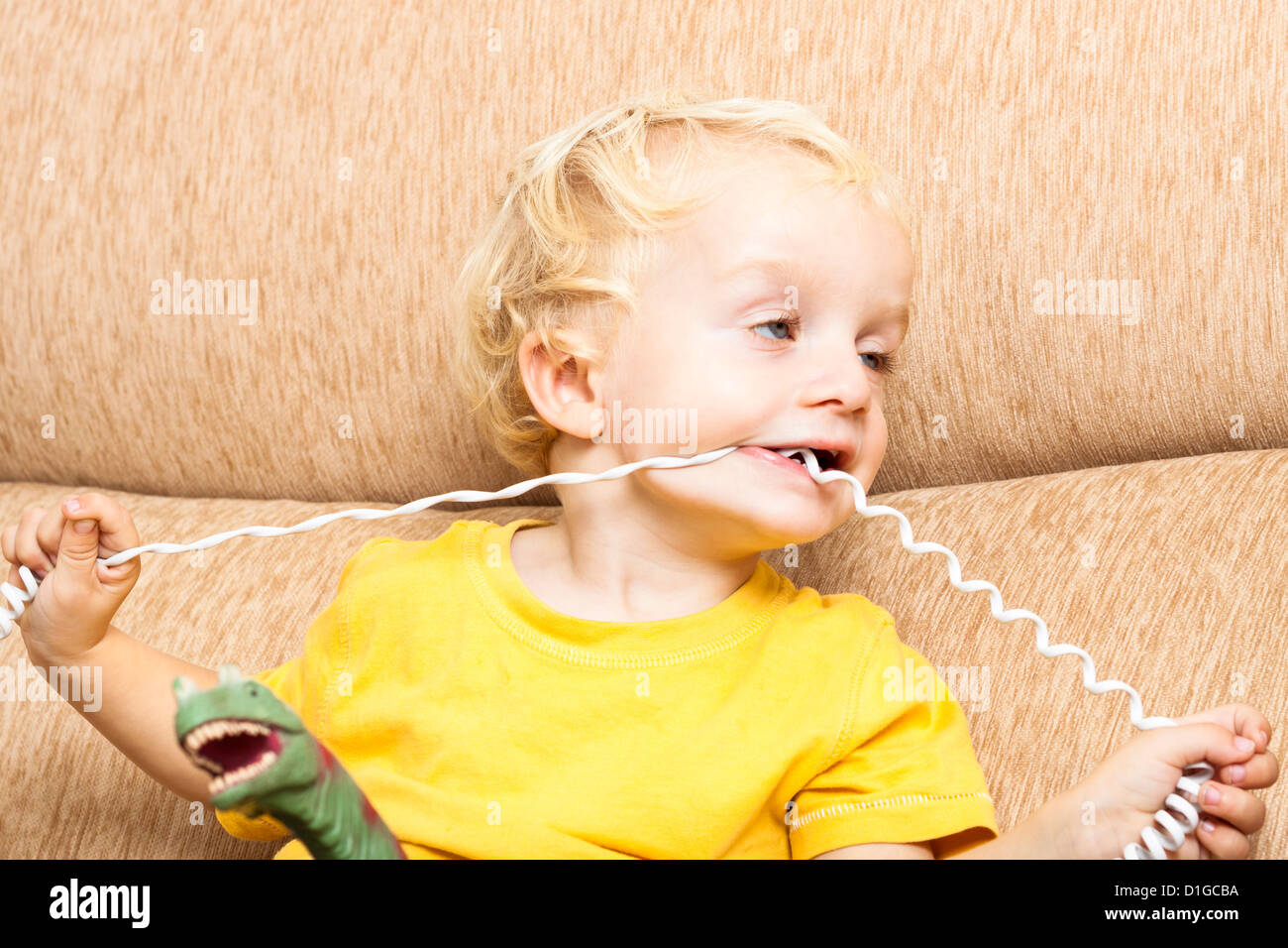 Close up of funny child boy biting phone wire Stock Photo - Alamy