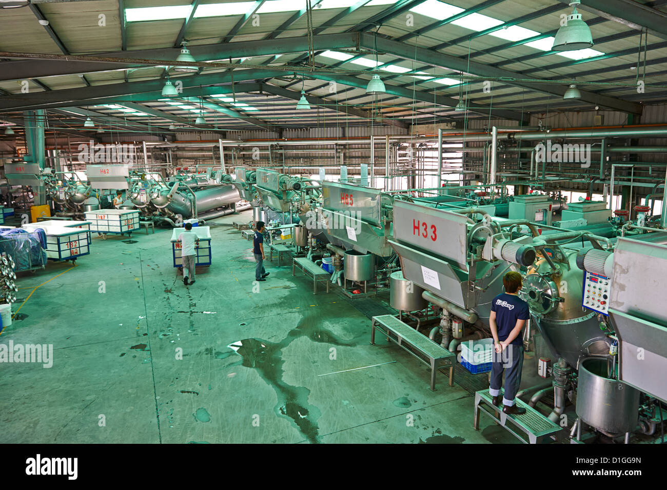 Inside a textile and fabric factory, here a worker pushes a giant bin ...