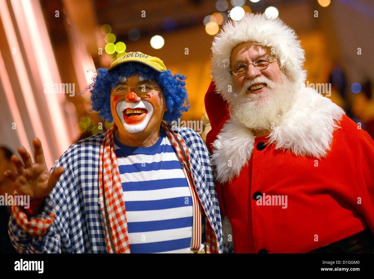 Two men dressed as a clown and as Santa Claus provide emtertainment at ...
