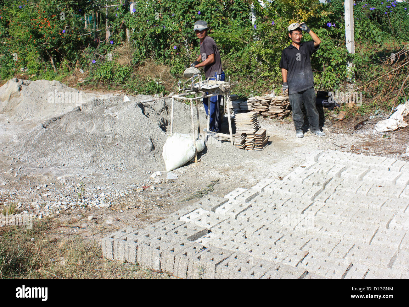 Two workers manufacture concrete blocks for construction work near the ...