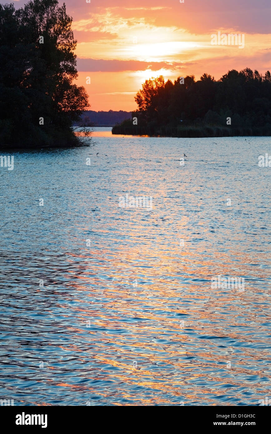 Pink-yellow sunset and sun reflection on lake water surface Stock Photo ...