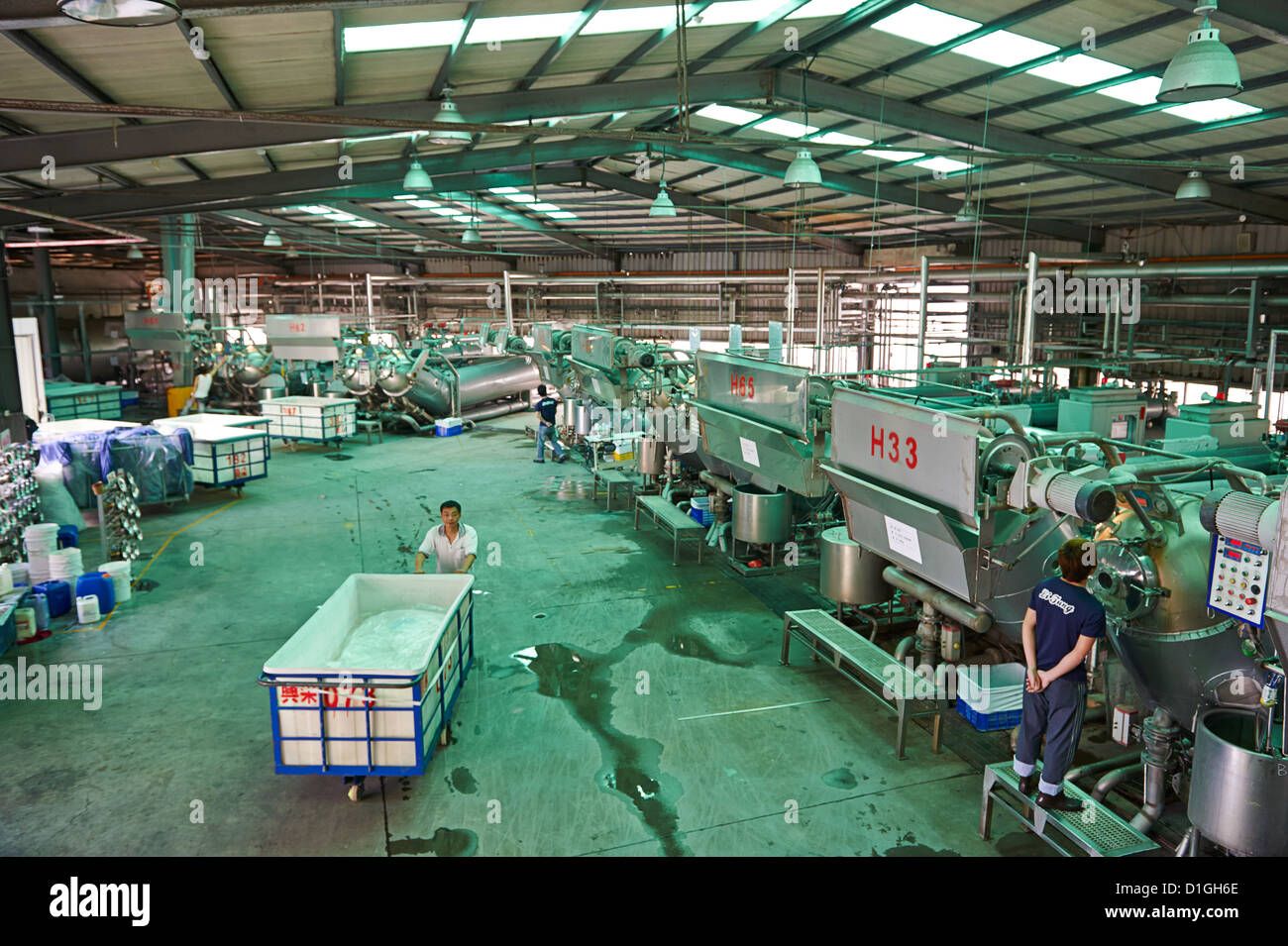 Inside a textile and fabric factory, here a worker pushes a giant bin ...
