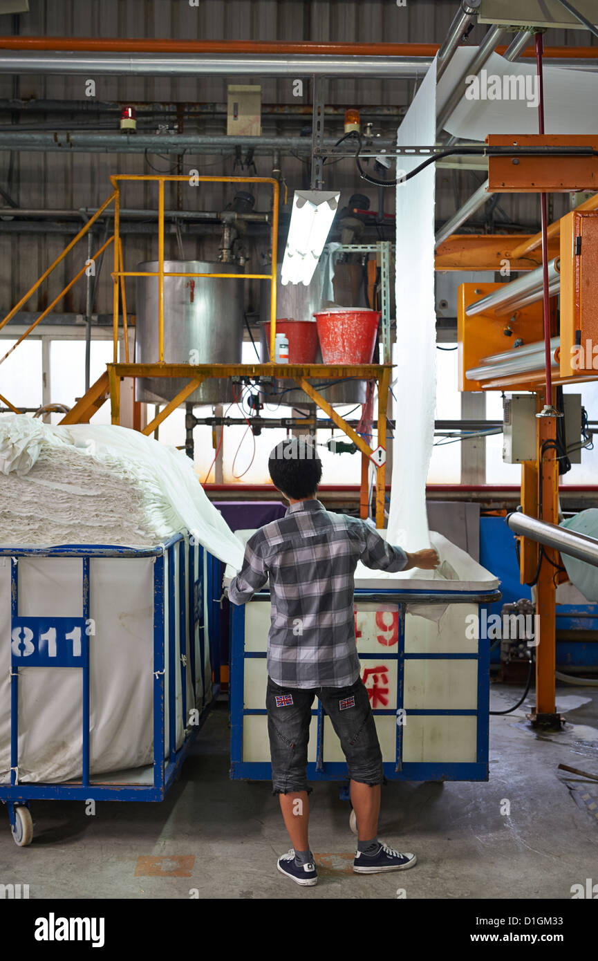Workers inspecting pressed fabric from pressing and rolling machines at ...