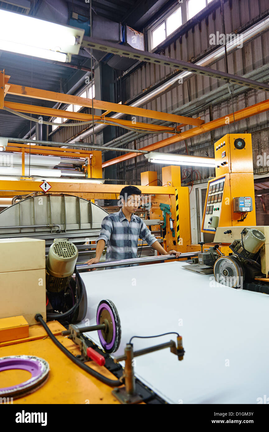 Workers inspecting pressed fabric from pressing and rolling machines at ...