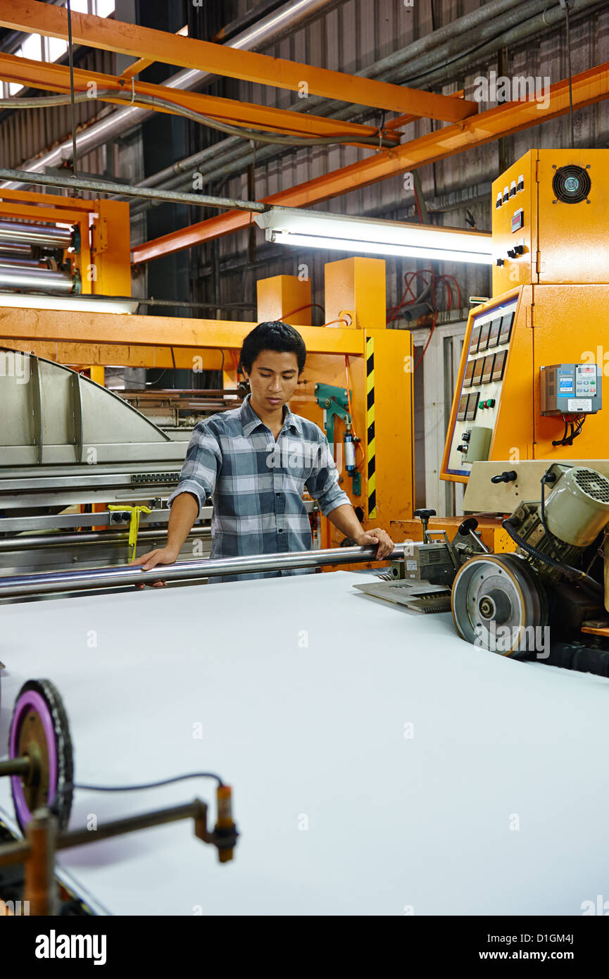 Workers inspecting pressed fabric from pressing and rolling machines at ...