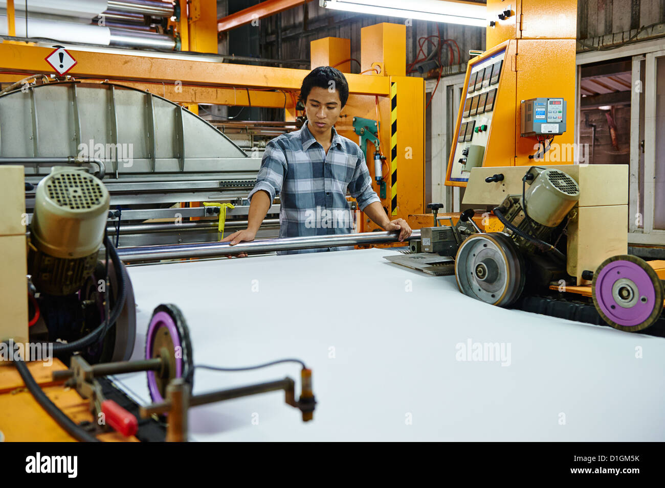 Workers inspecting pressed fabric from pressing and rolling machines at ...