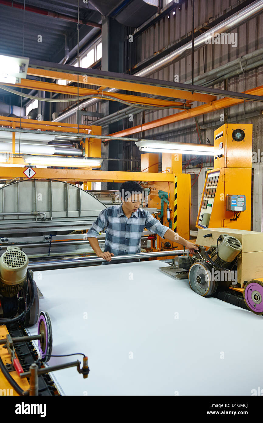 Workers inspecting pressed fabric from pressing and rolling machines at ...