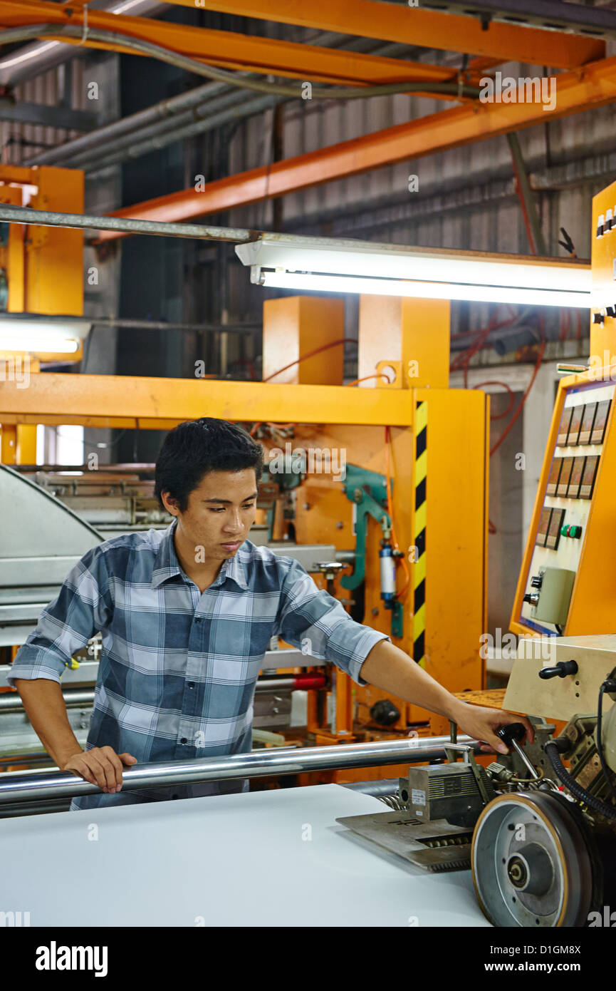 Workers inspecting pressed fabric from pressing and rolling machines at ...