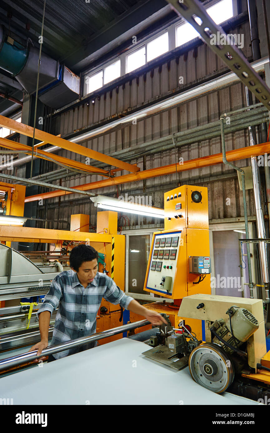 Workers inspecting pressed fabric from pressing and rolling machines at ...