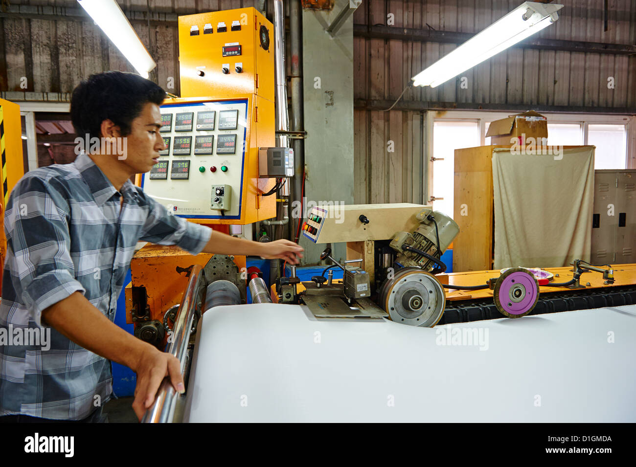 Workers inspecting pressed fabric from pressing and rolling machines at ...